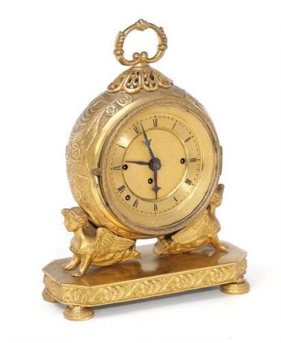 A small Austrian gilt bronze table clock, round clock case supported by ...
