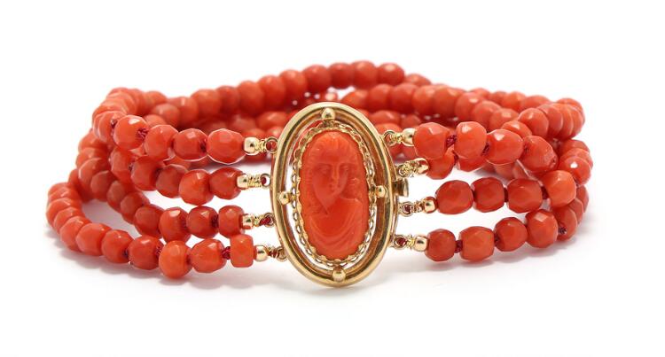 A four-string coral bracelet set with numerous coral beads and a carved ...