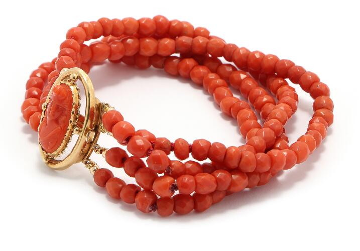 A four-string coral bracelet set with numerous coral beads and a carved ...