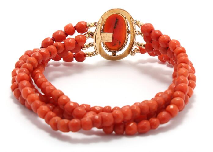 A four-string coral bracelet set with numerous coral beads and a carved ...