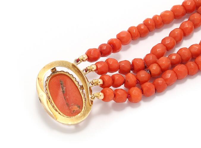 A four-string coral bracelet set with numerous coral beads and a carved ...